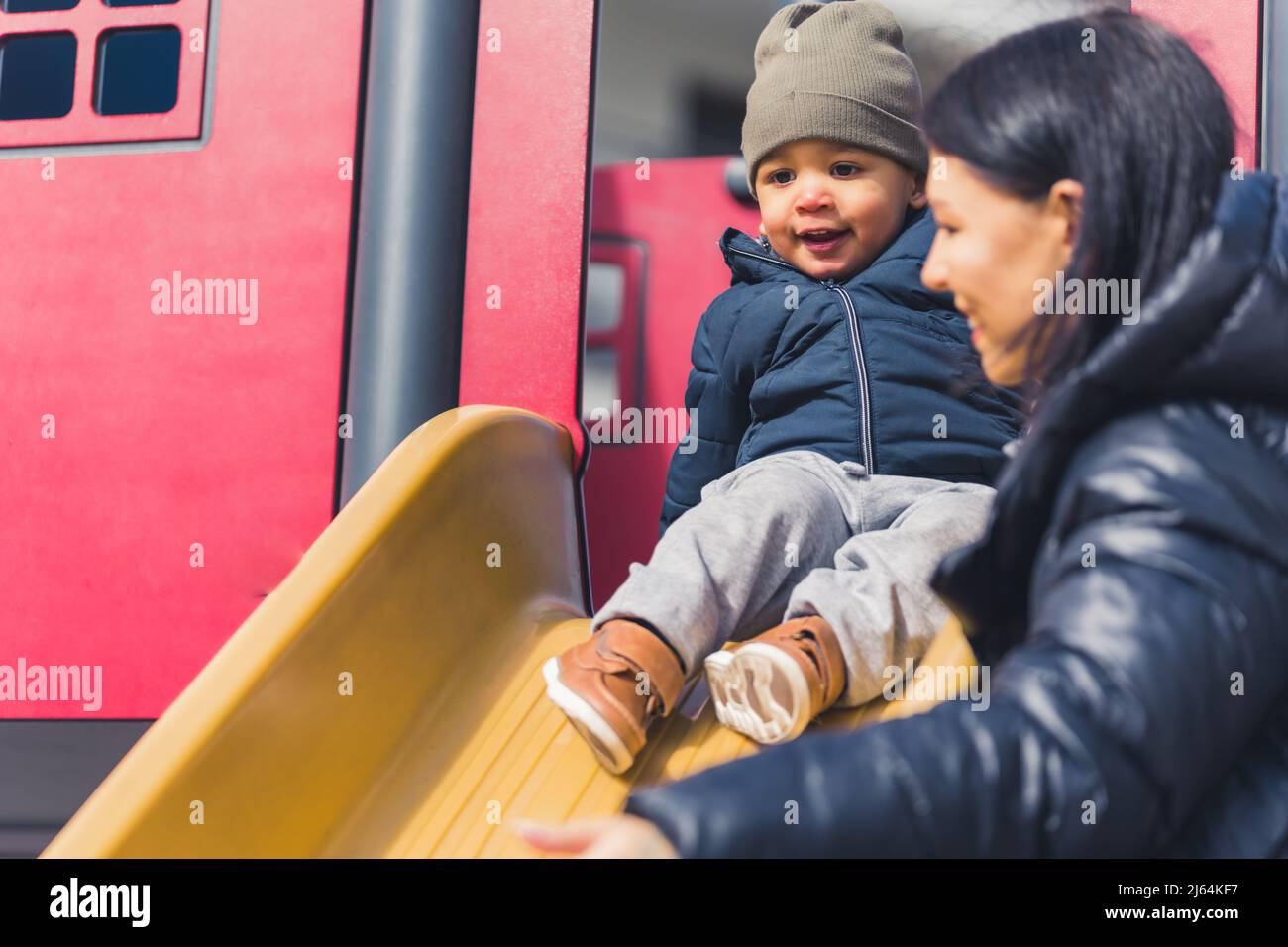 Curious multiracial toddler boy in warm clothes playing on the ...