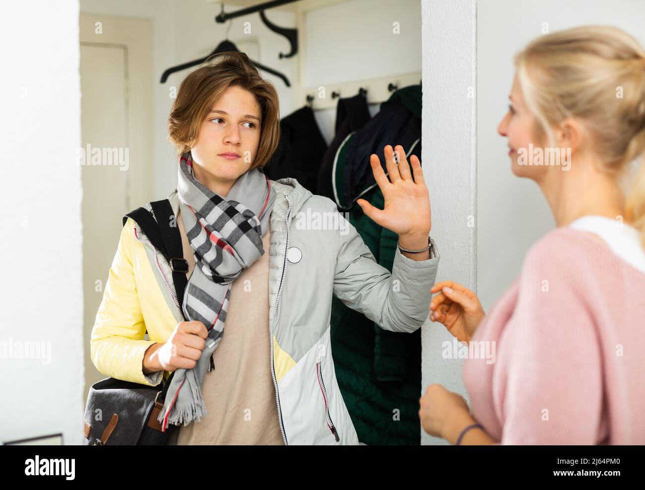 Teenage boy gesturing goodbye to mother while leaving home Stock Photo ...