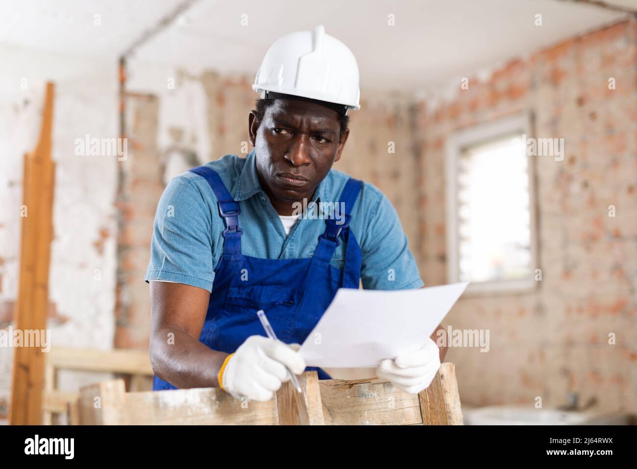 Frustrated african american foreman standing with papers at ...