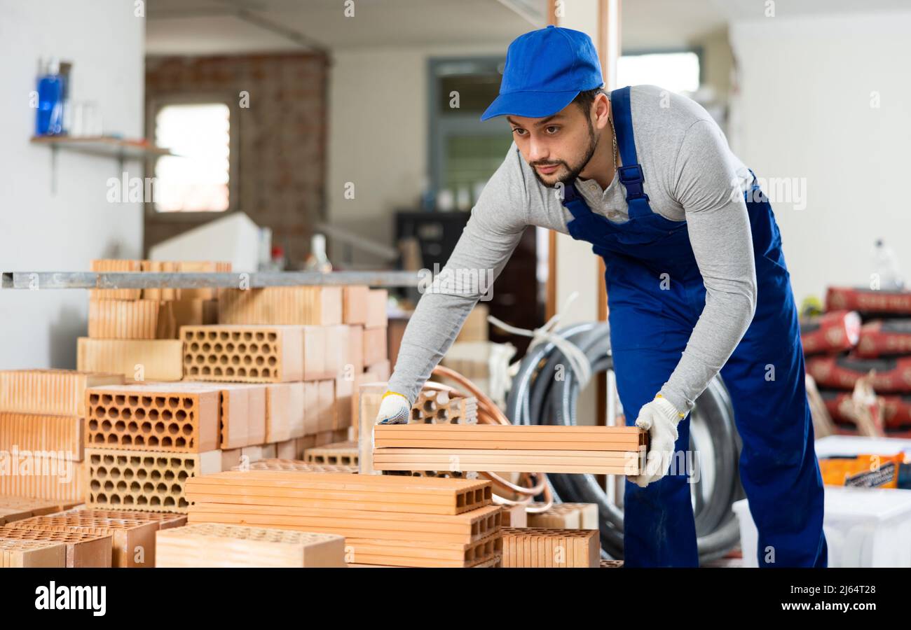 Young man stacking bricks at construction site Stock Photo - Alamy