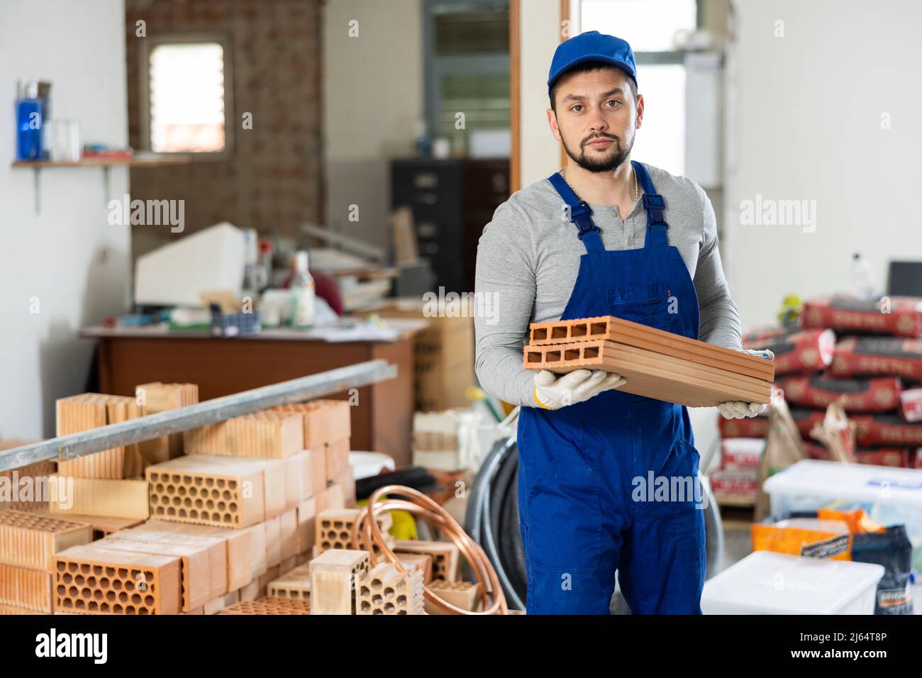 Young man stacking bricks at construction site Stock Photo - Alamy