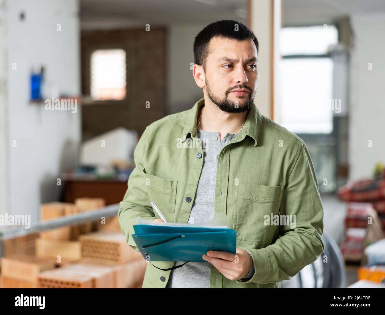 Engineer makes notes, holding a folder with documents Stock Photo - Alamy