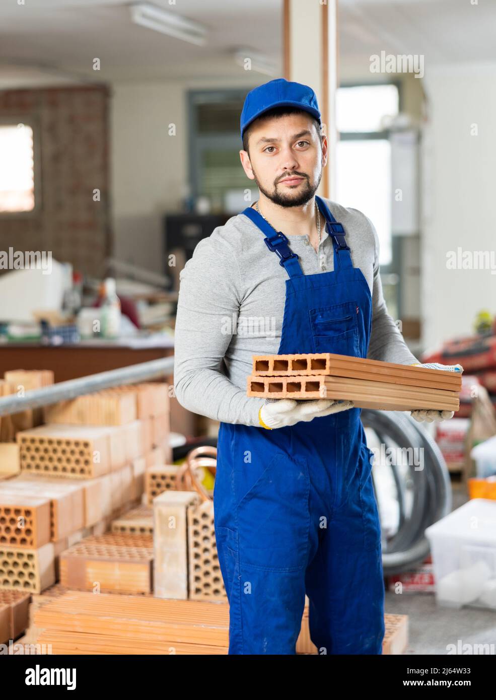 Builder preparing bricks for work in building under reconstruction ...