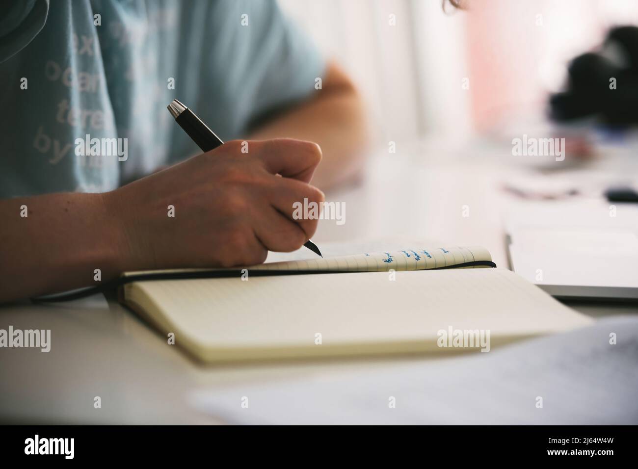 Side view of woman using fountain pen to write in her diary taking ...