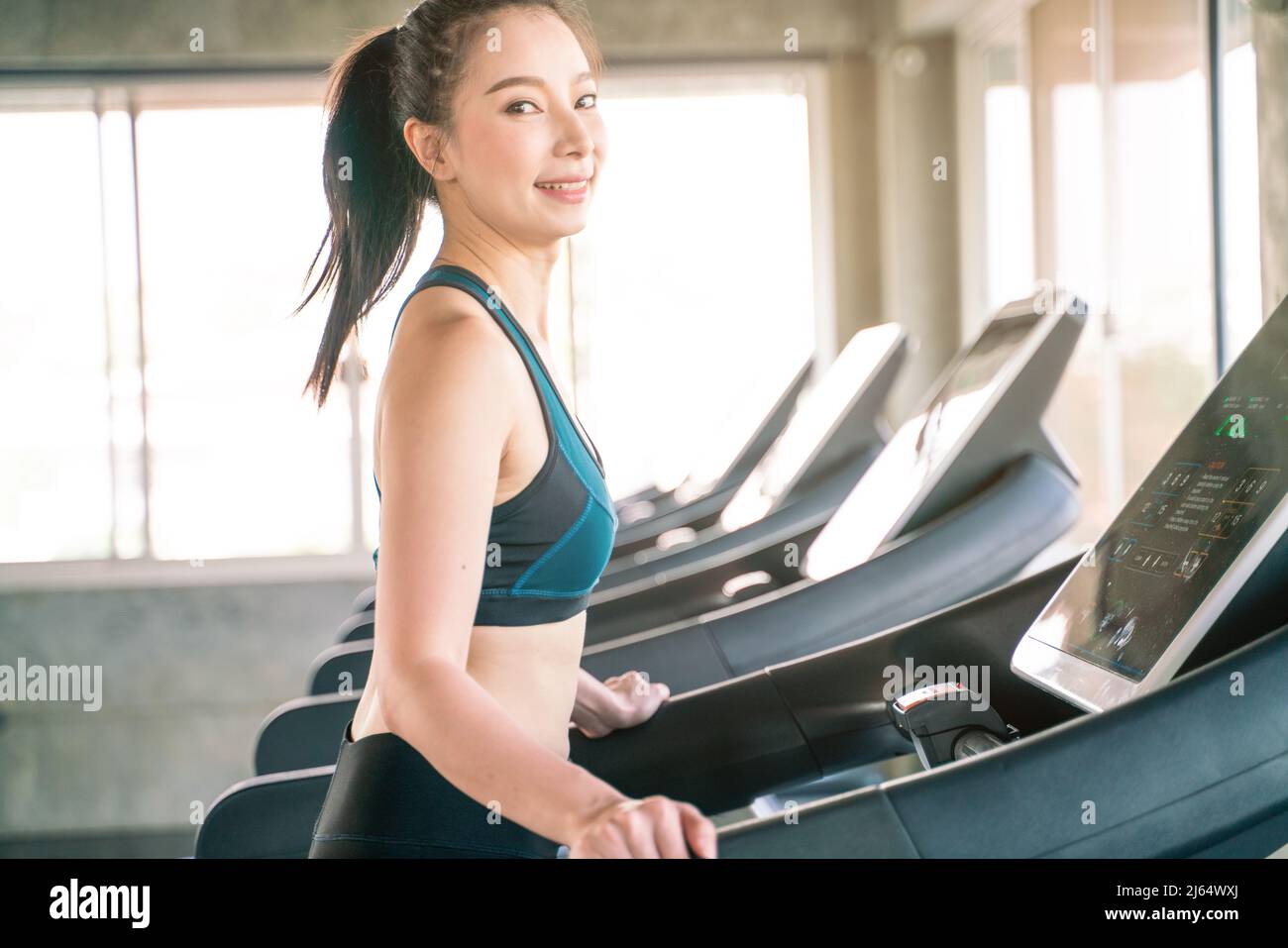 Asian woman jogging on a treadmill working out in gym, Cardio exercise ...