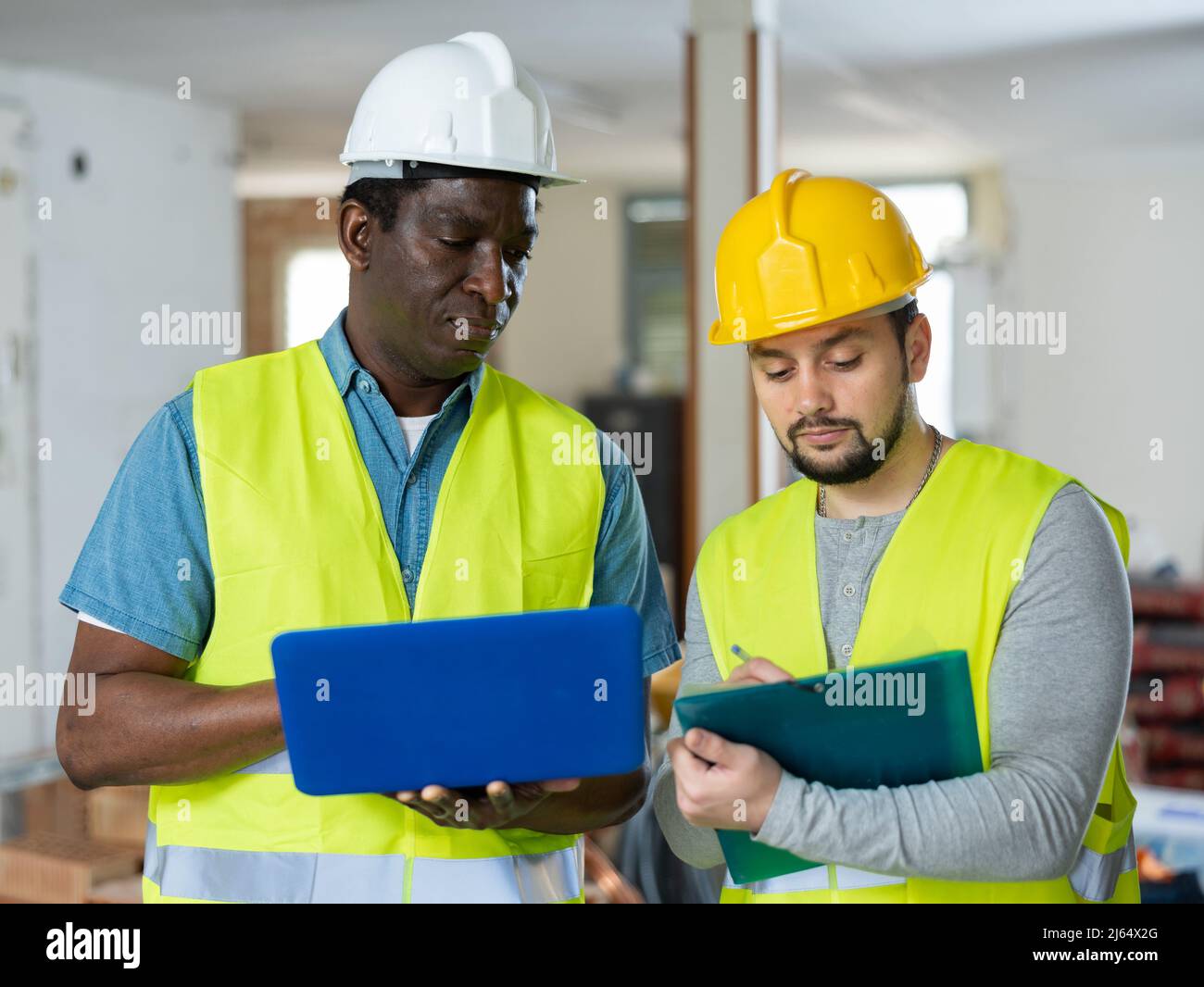 Two builders talking on indoor construction site Stock Photo - Alamy