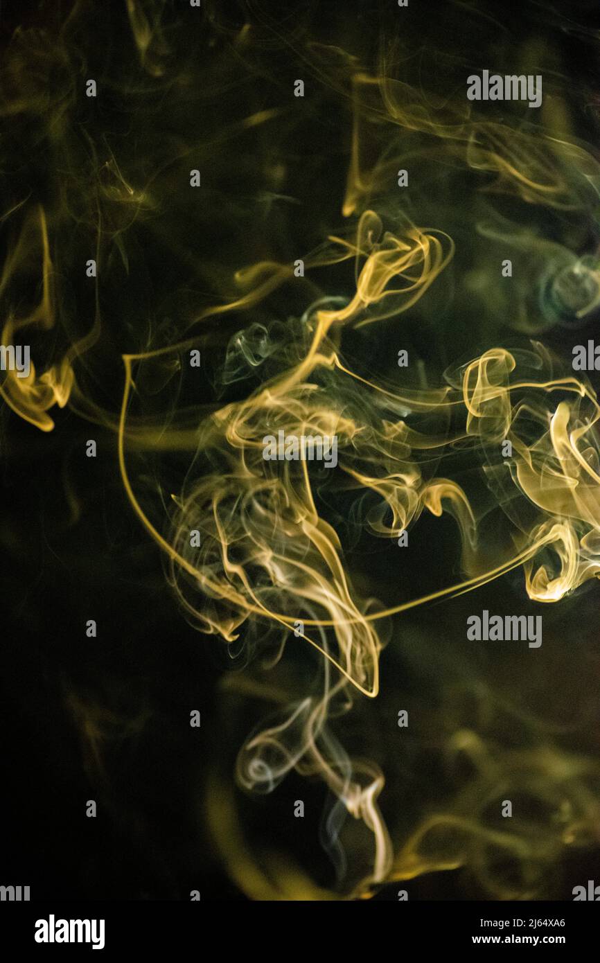 A yellow gold swirling, ascending smoke pattern on a black background ...