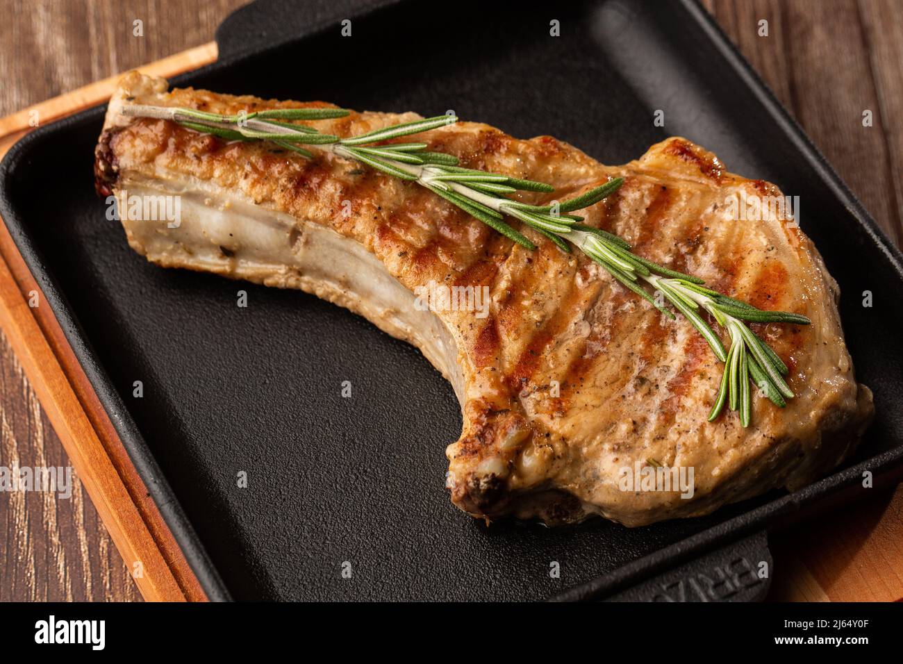 Roasted pork chop steak with spices and rosemary on black plate on ...