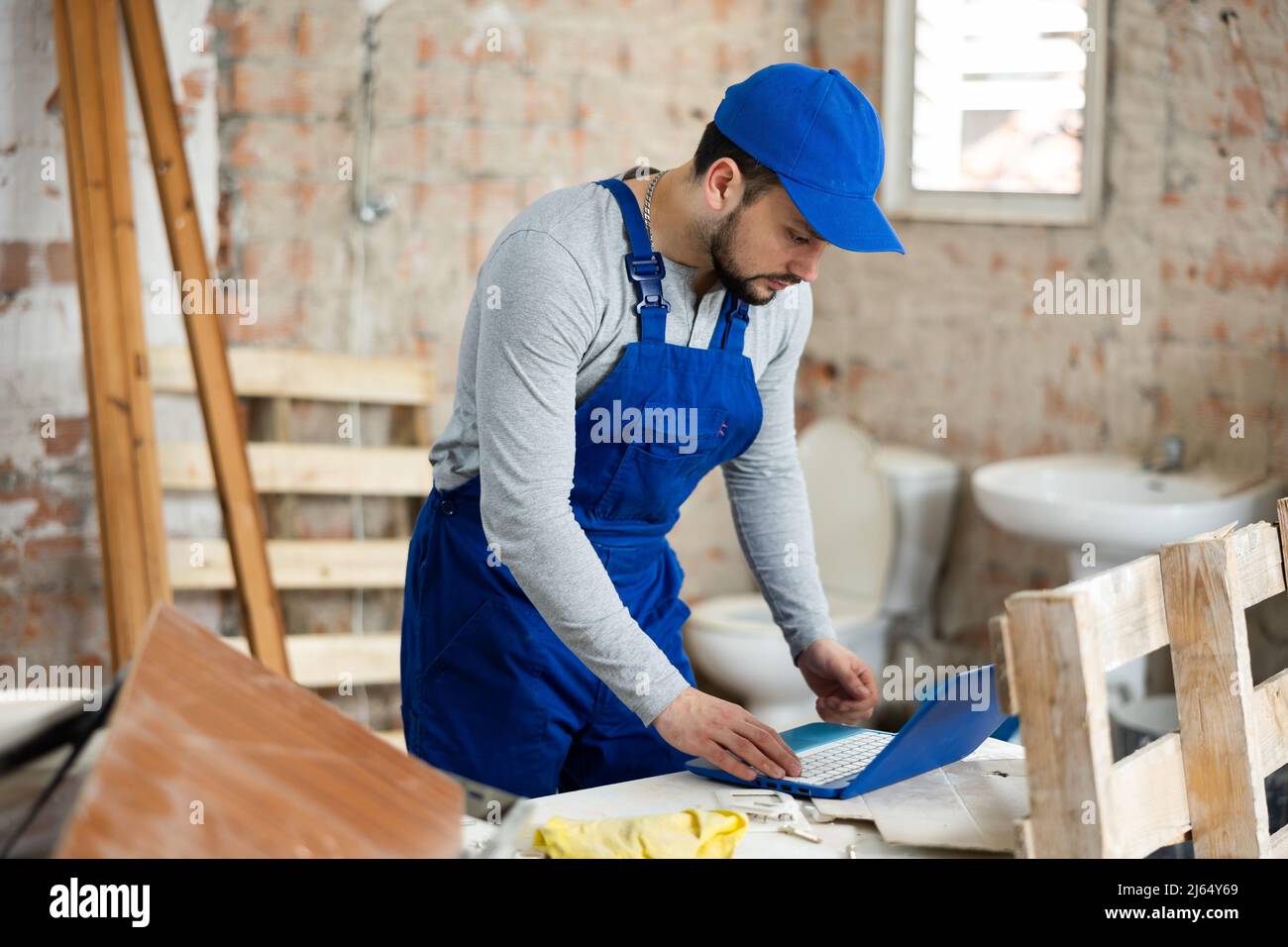 Builder handyman checking plan of house renovation on laptop Stock ...