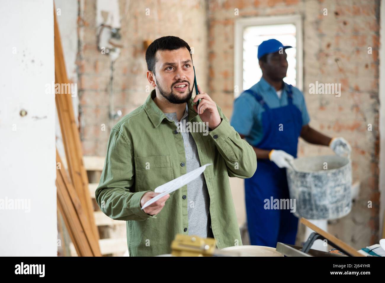 Irritated man talking phone at construction site Stock Photo - Alamy