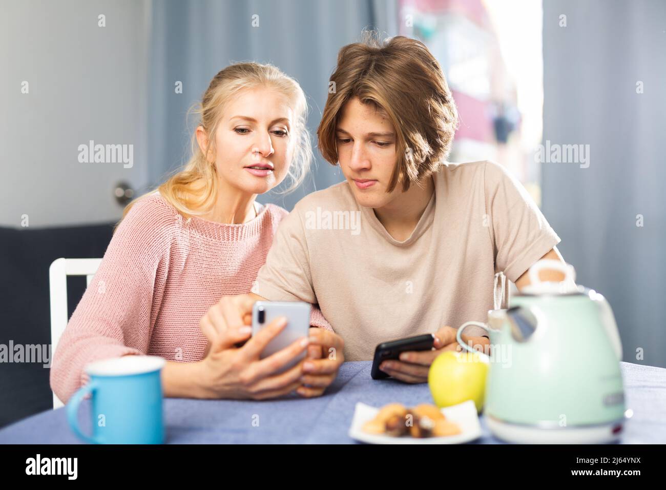 Teenager showing pictures on smartphone to interested mother Stock ...