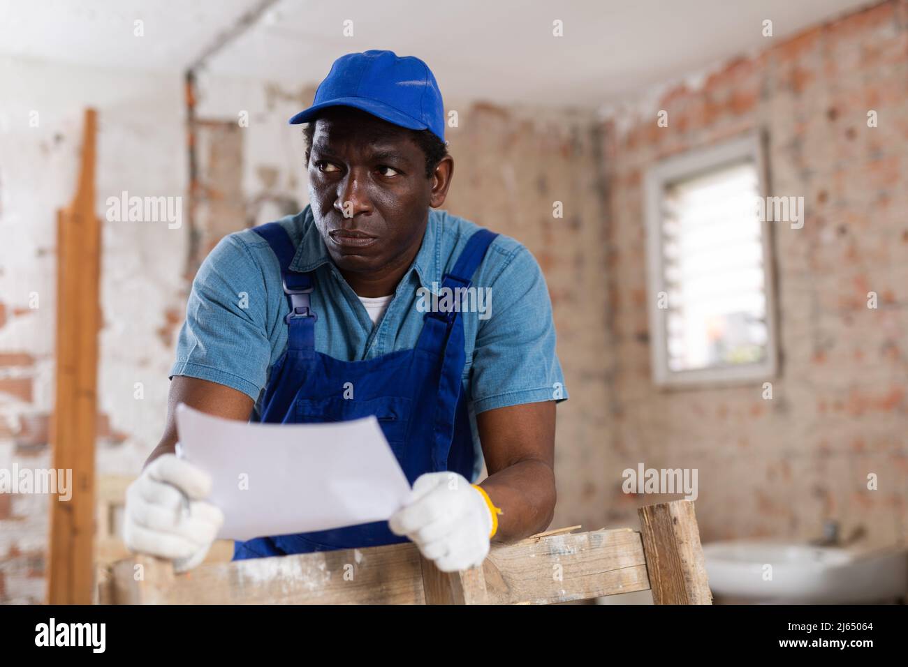 Upset african american contractor standing with papers at construction ...
