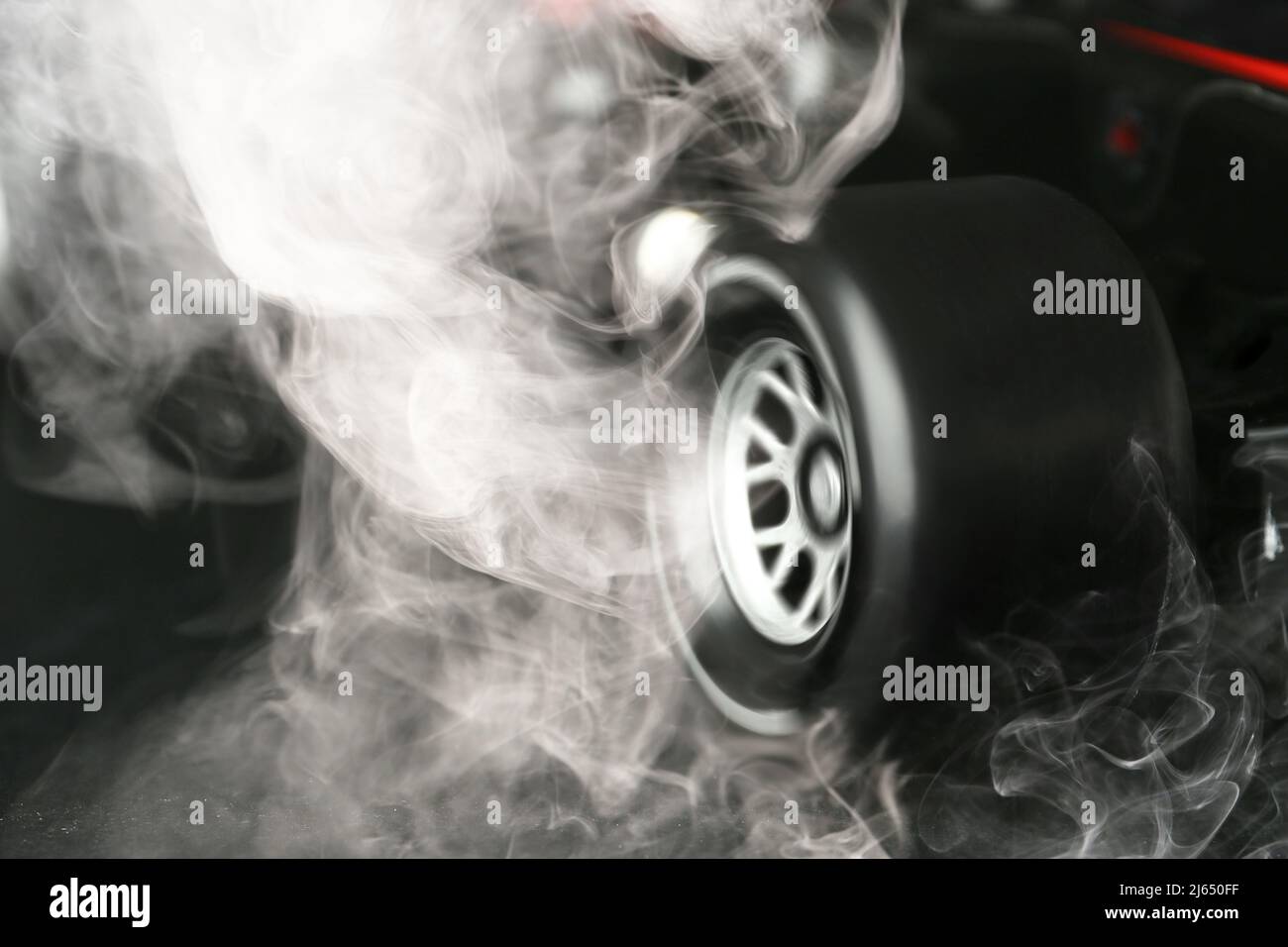 Modern racing car with smoke from under wheels on dark background ...