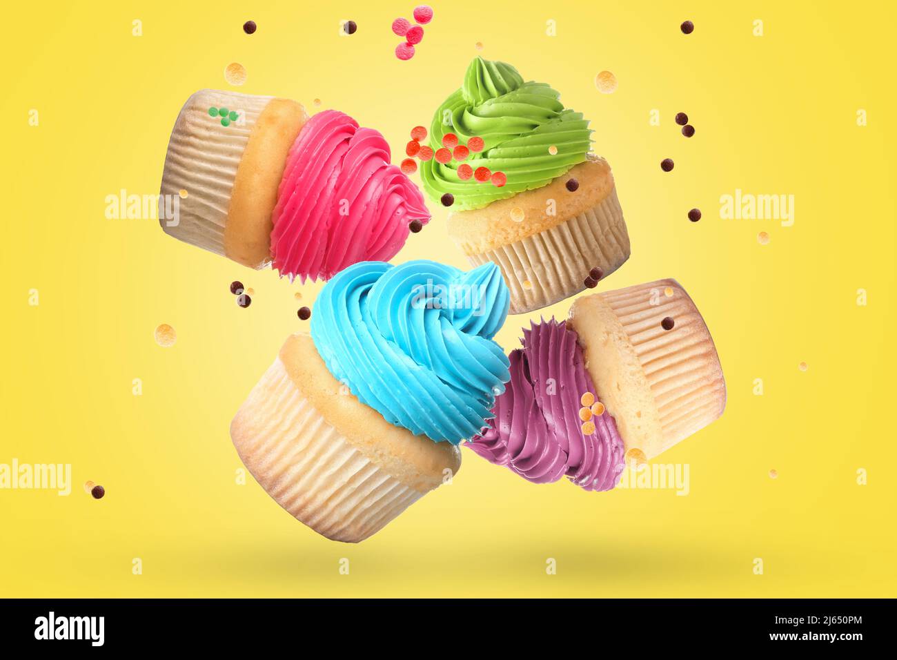 Tasty flying cupcakes on yellow background Stock Photo - Alamy
