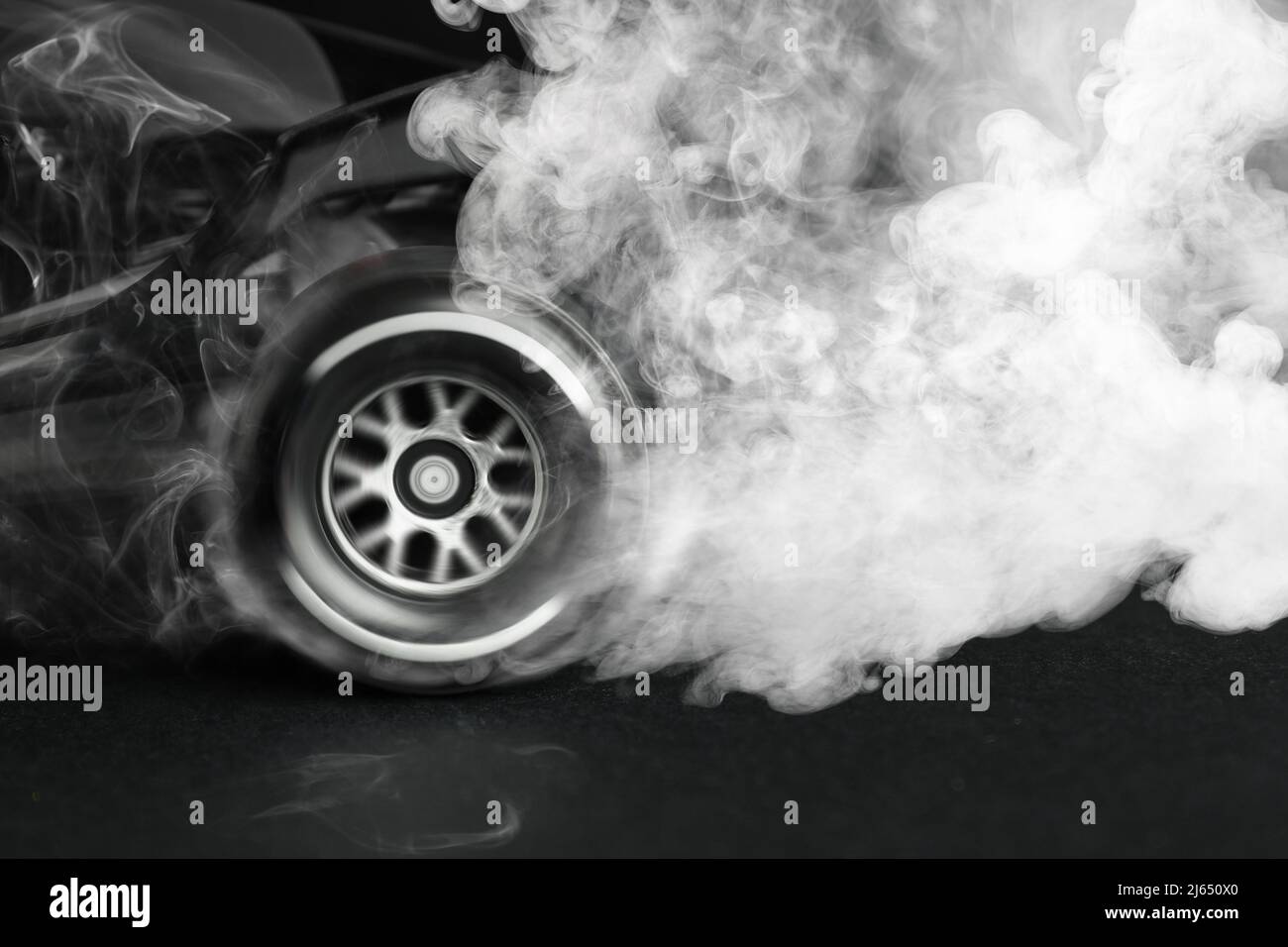 Modern racing car with smoke from under wheels on dark background ...