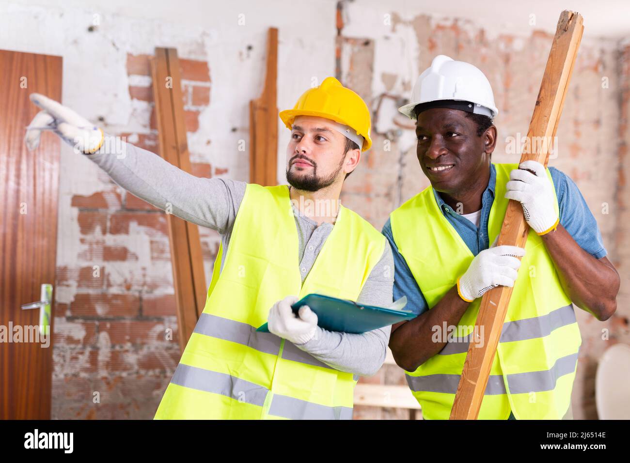 Builders discussing work in cosntruction site Stock Photo - Alamy