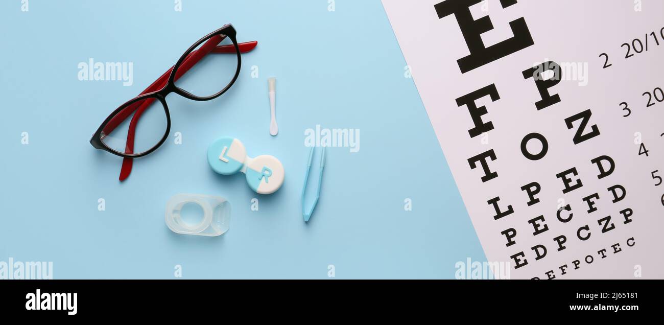 Contact lenses, eye test chart and glasses on light blue background ...