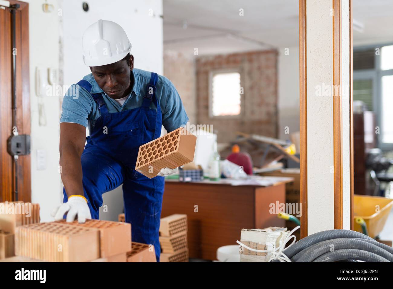 African american builder stacking bricks in building under renovation ...