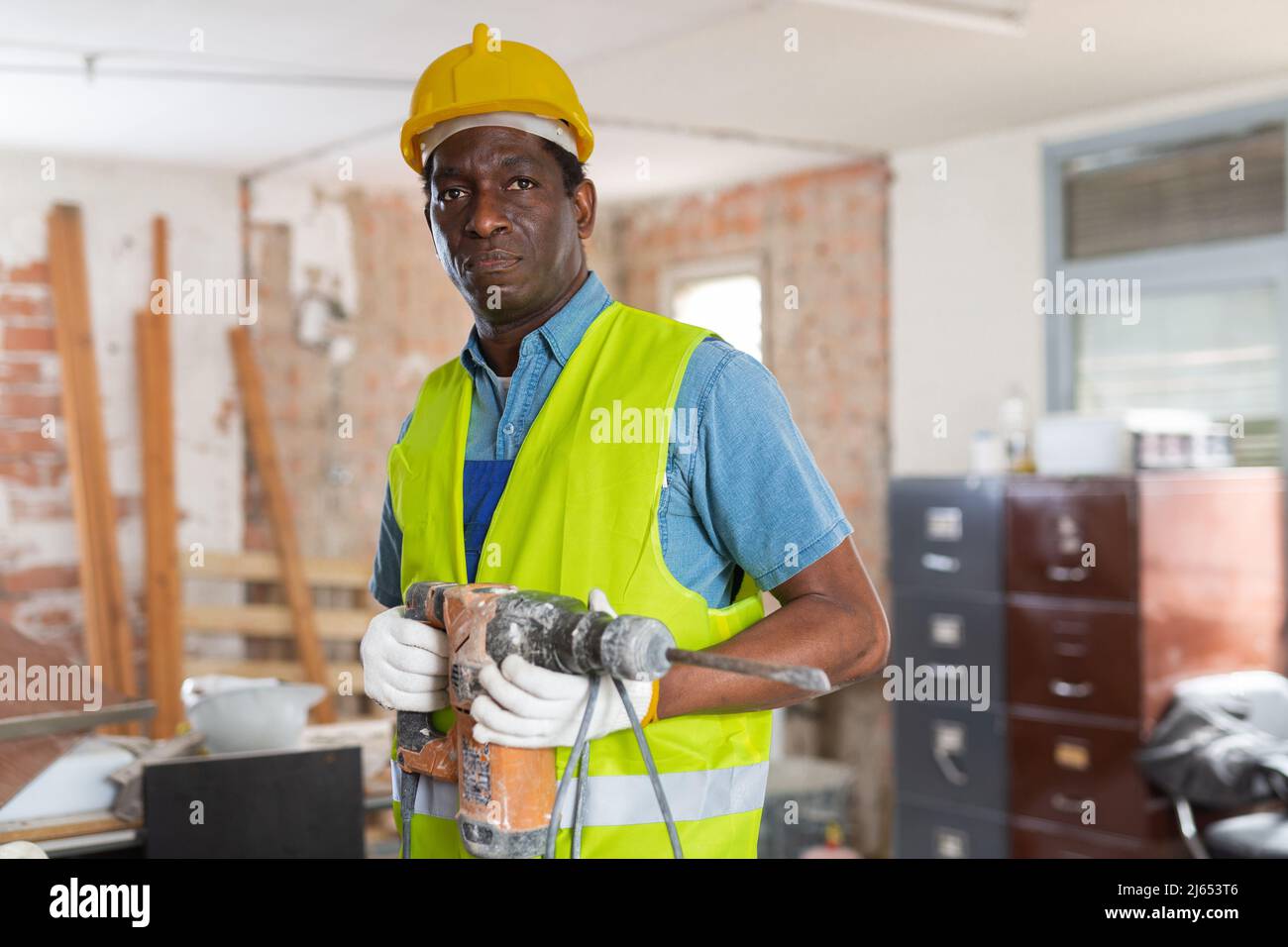 Professional builder holding pneumatic chipping hammer in building ...