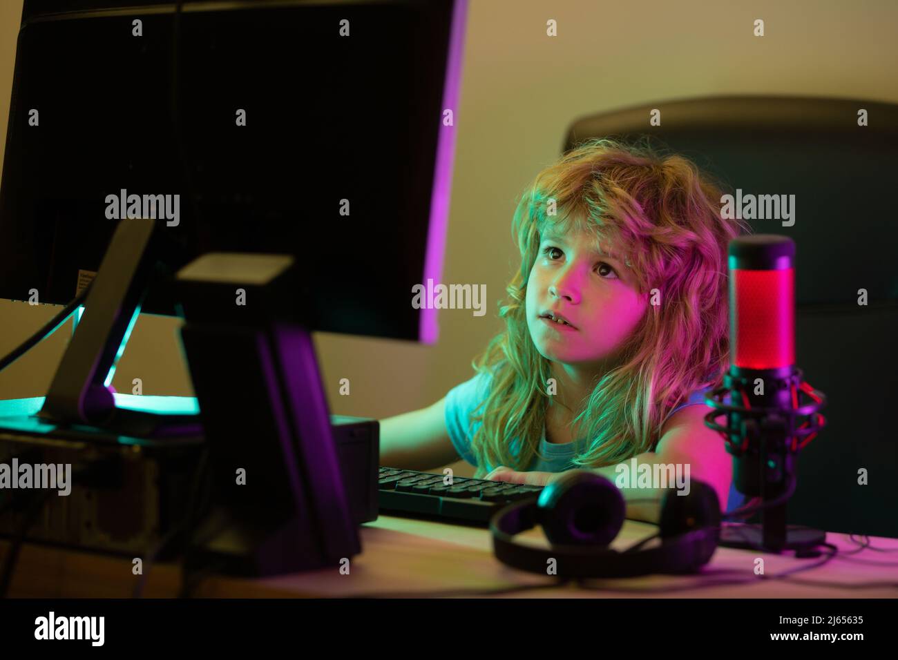 Little kid using desktop pc by night, child boy illuminated by the blue ...