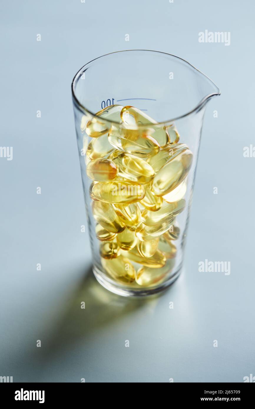 Capsules of omega-3 fatty acids on a blue background in a glass. The ...