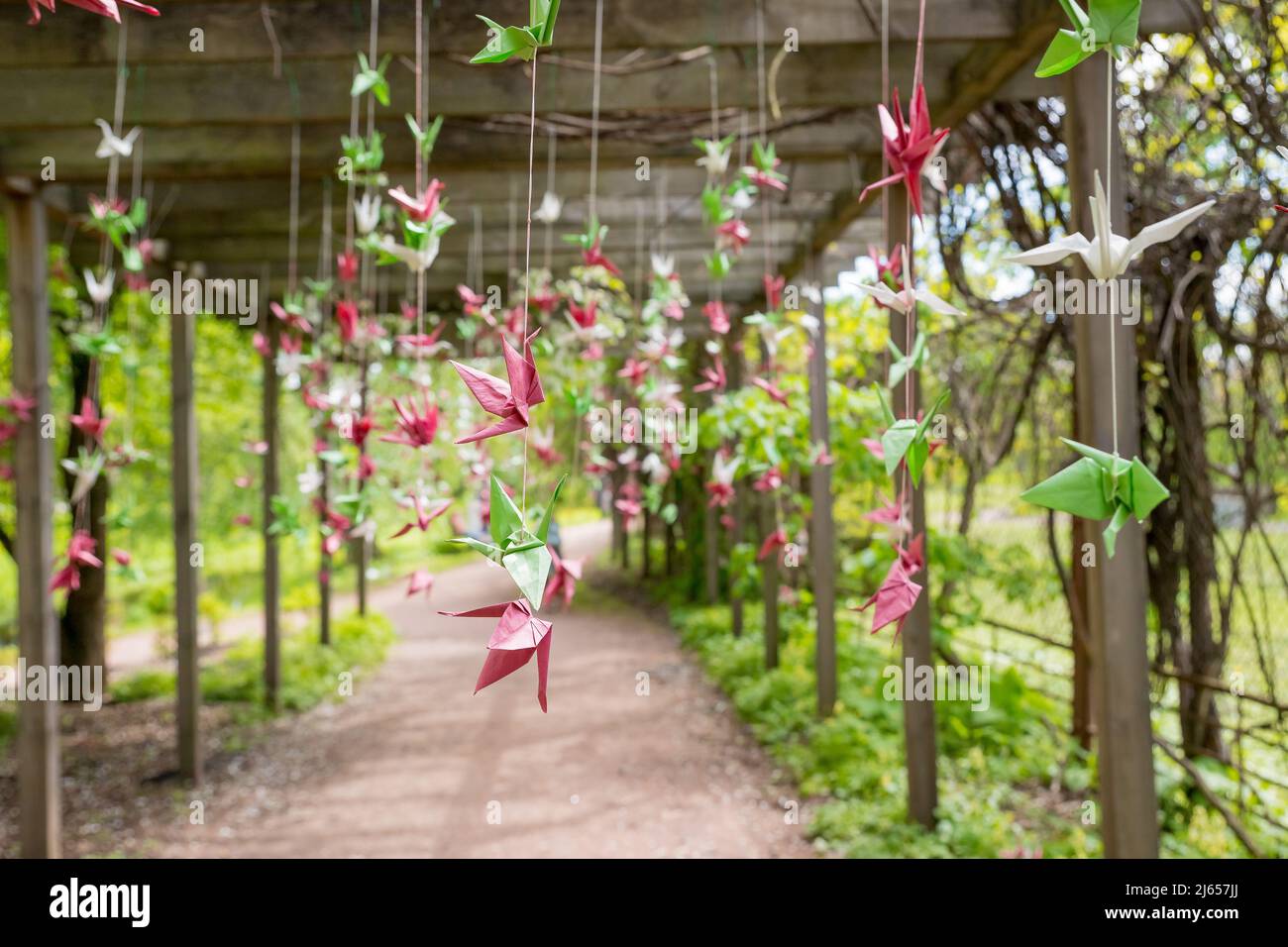 origami crane birds hanging on the threads in the garden Stock Photo ...