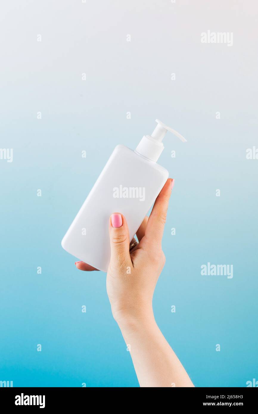 A mockup of a white dispenser with a cosmetic product in a woman's hand ...