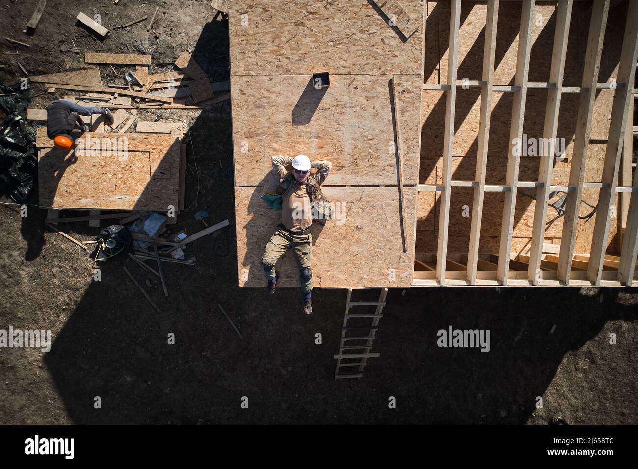 Portrait of male worker building wooden frame house. Top view man ...