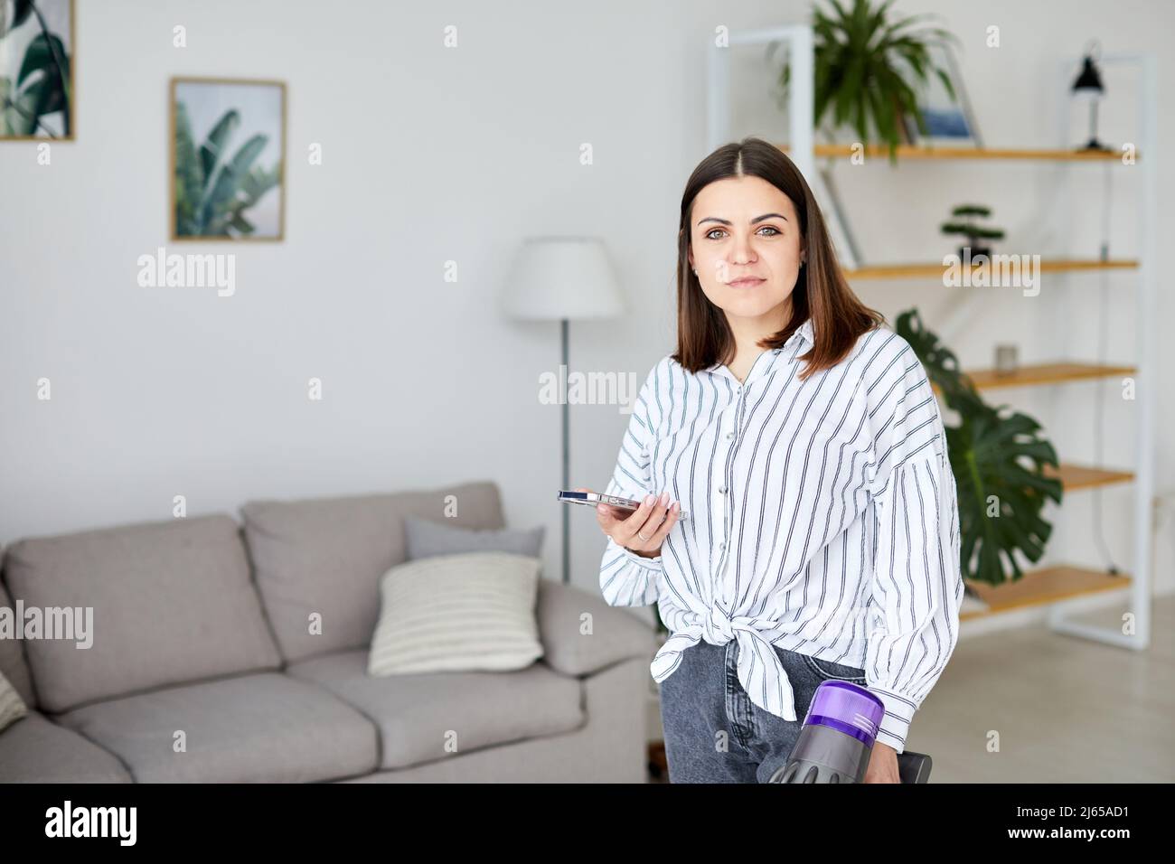 Happy cheerful young Caucasian beautiful woman vacuuming floor and ...