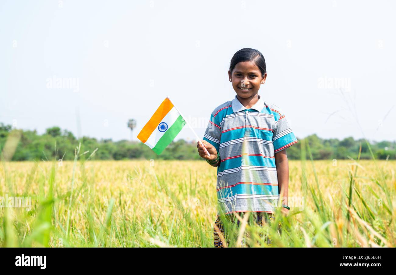 Happy smiling Indian village girl with Indian flag standing in middle ...