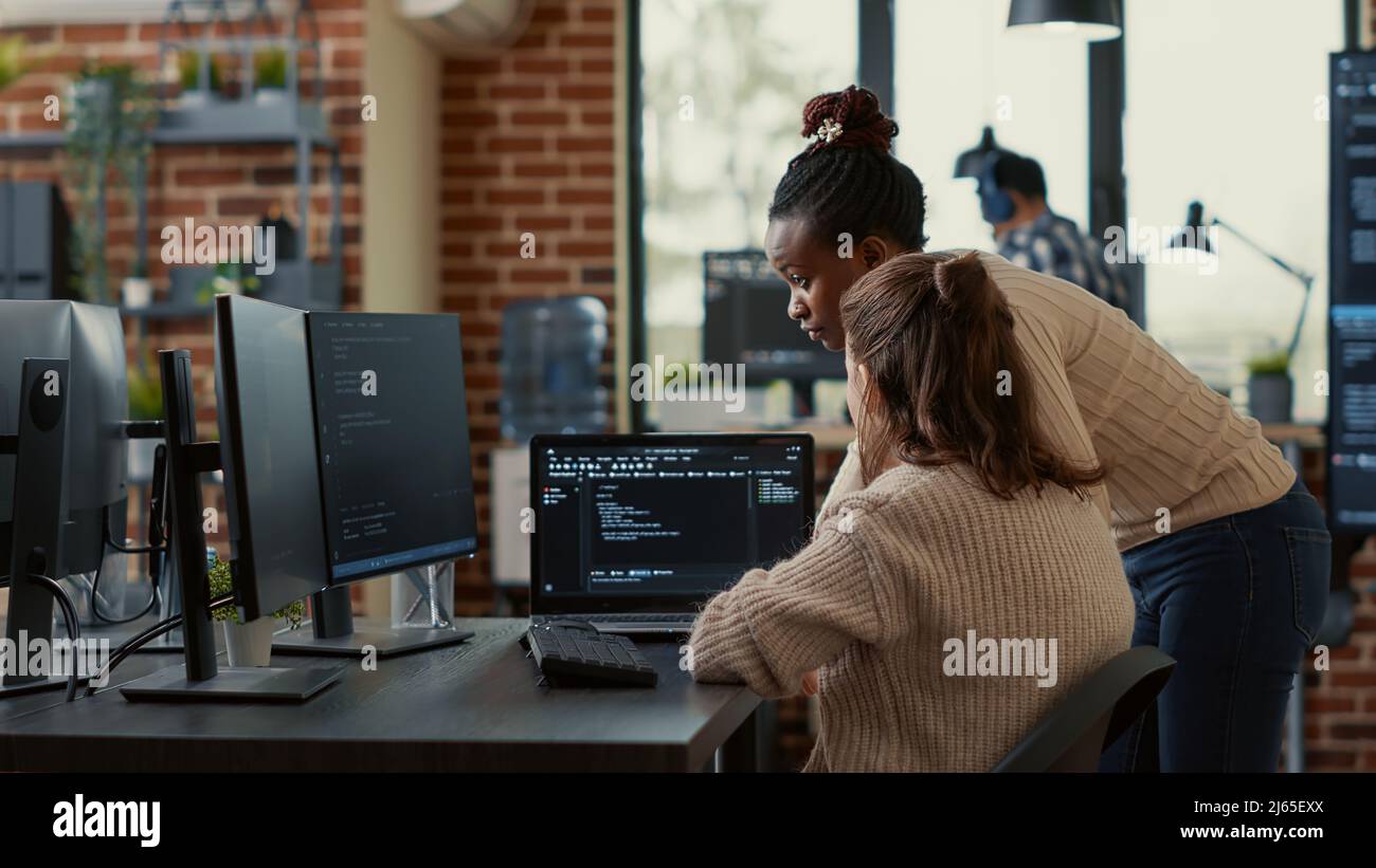 Two System Engineers Analyzing Source Code On Laptop Looking For Errors On Screen While Sitting