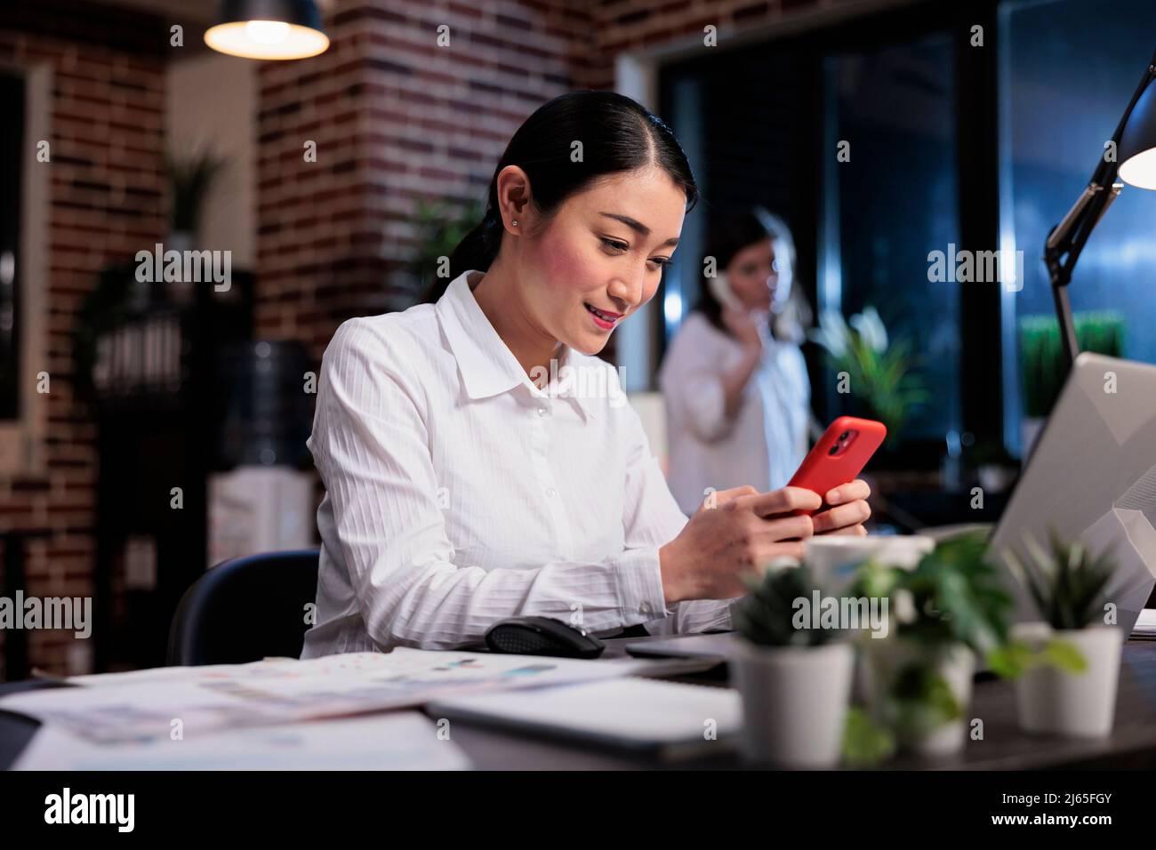 Happy smiling asian office worker sitting in office workspace while ...
