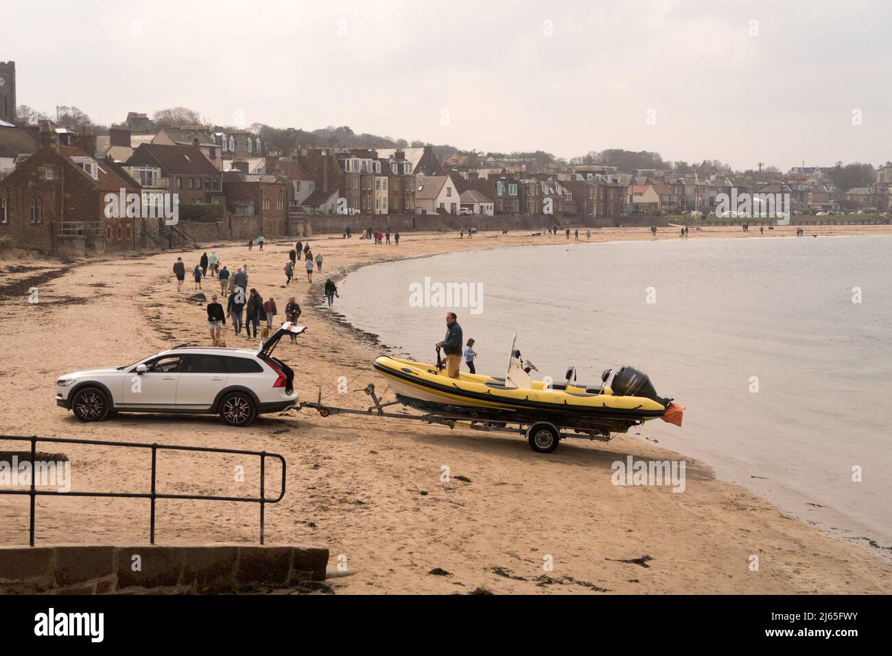 A man loading a inflatable motor boat onto a trailer on the beach in ...