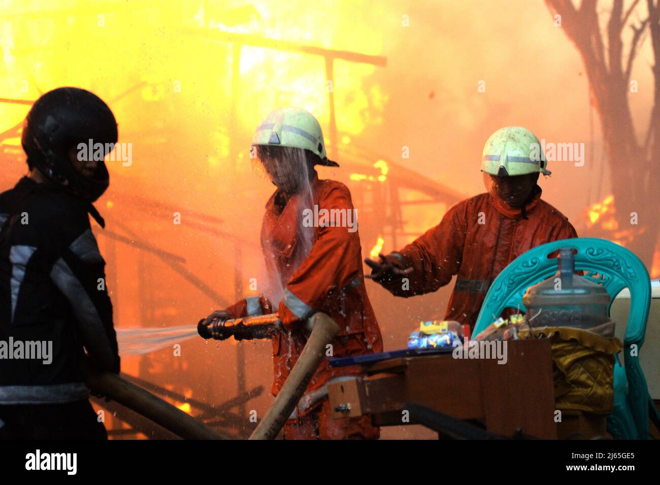 Firefighters trying to manage a leaked fire hose as a fire accident ...