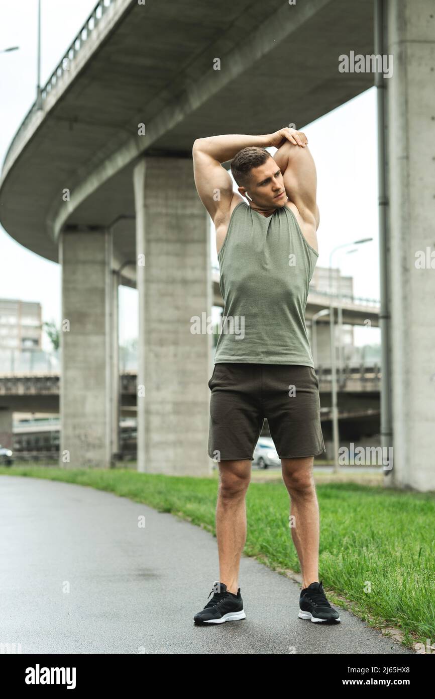 Muscular man warming up before his outdoor fitness workout Stock Photo ...