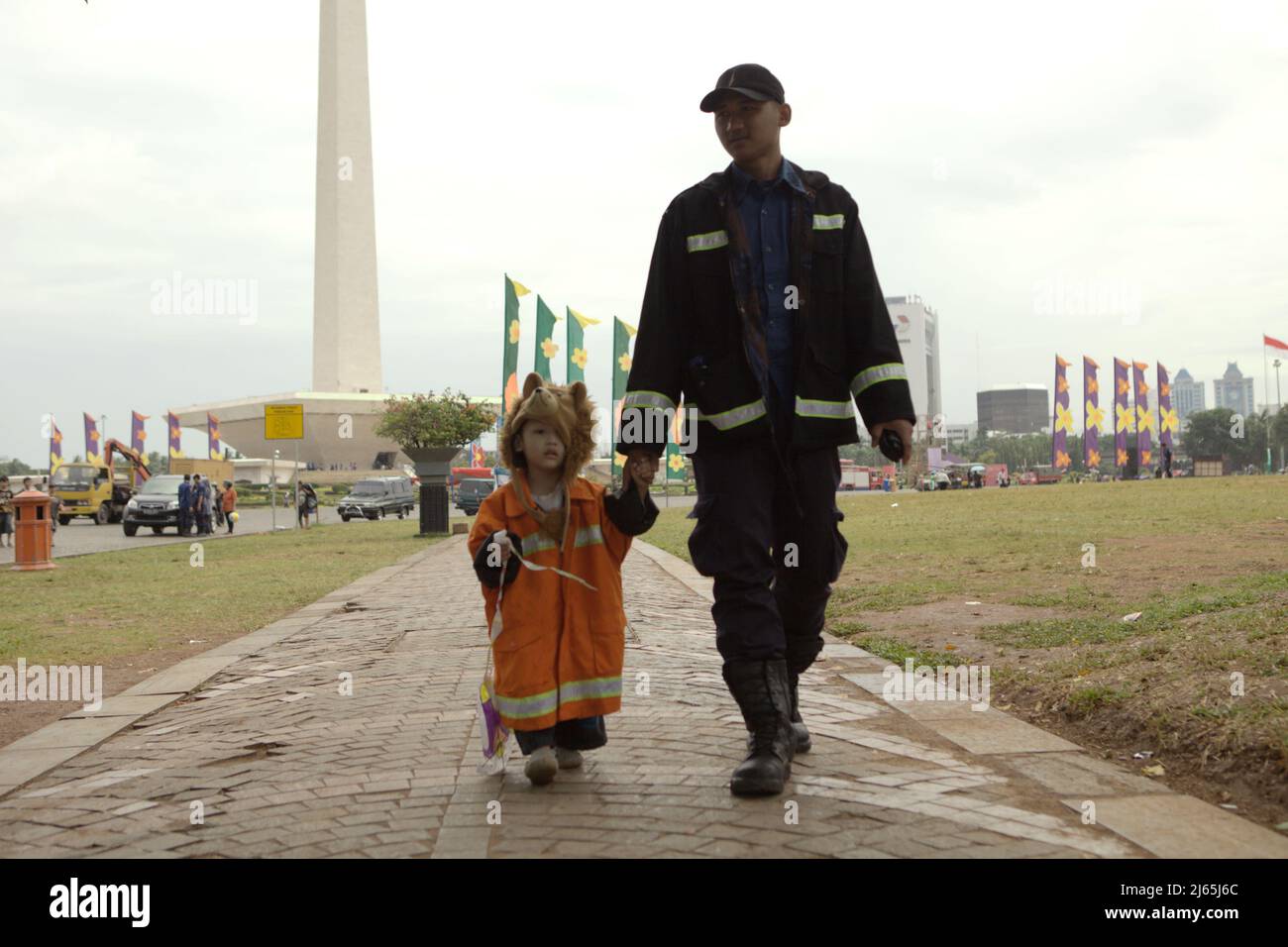 A member of Jakarta's firefighting squad walking with his daughter who ...