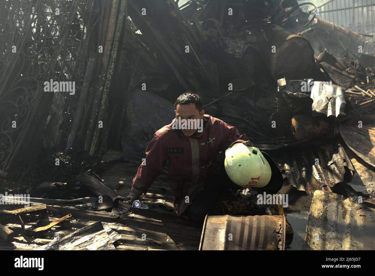 An exhausted firefighter resting between debris after a fire accident ...