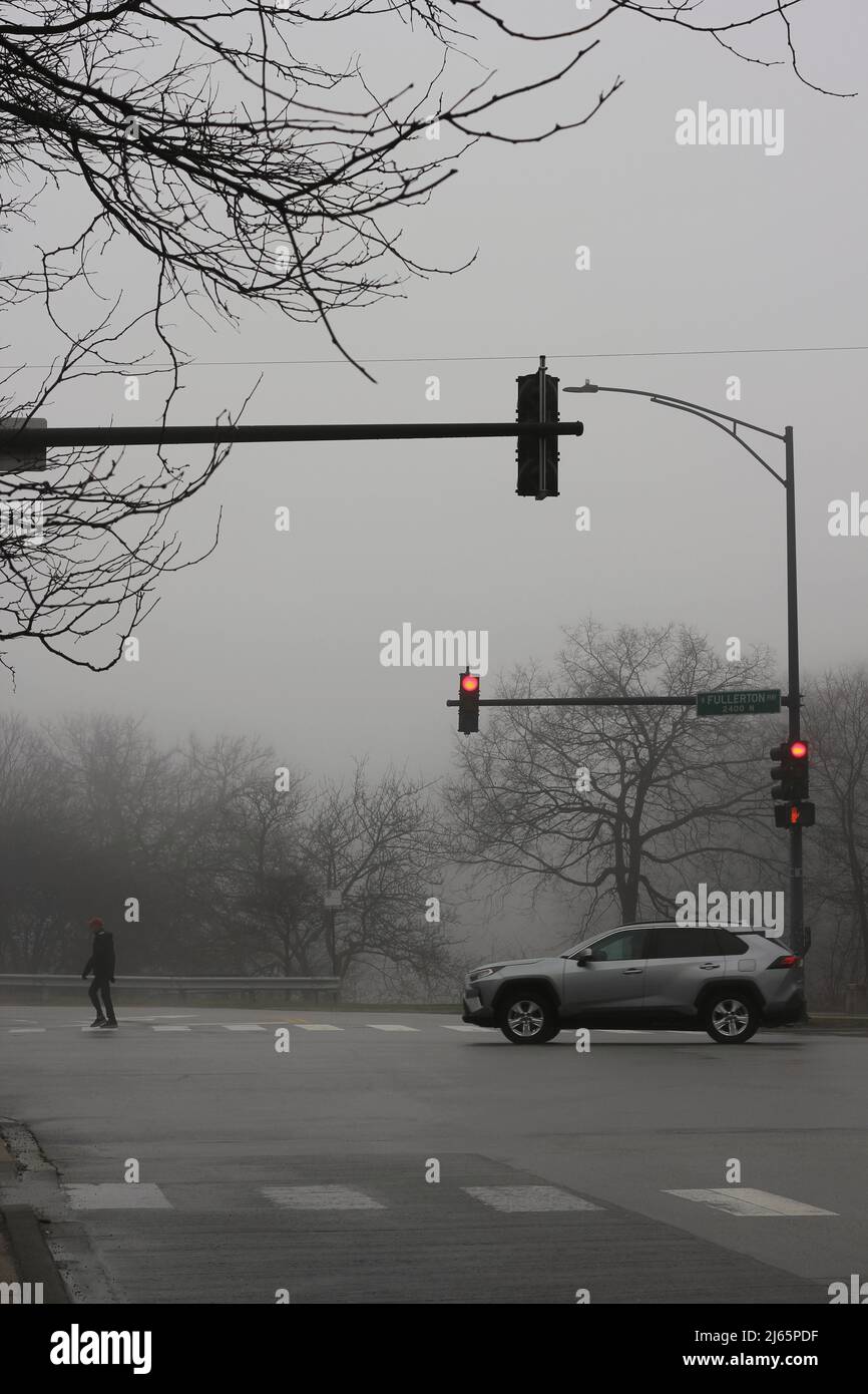 A person crossing the street at the intersection on a very foggy day ...