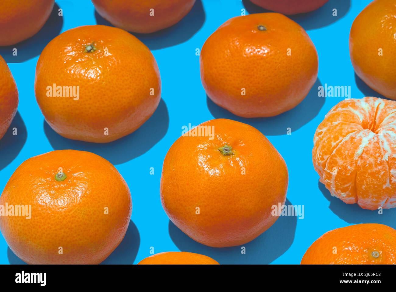 A Peeled Tangerine Among Other Tangerines on a Light Blue Background ...