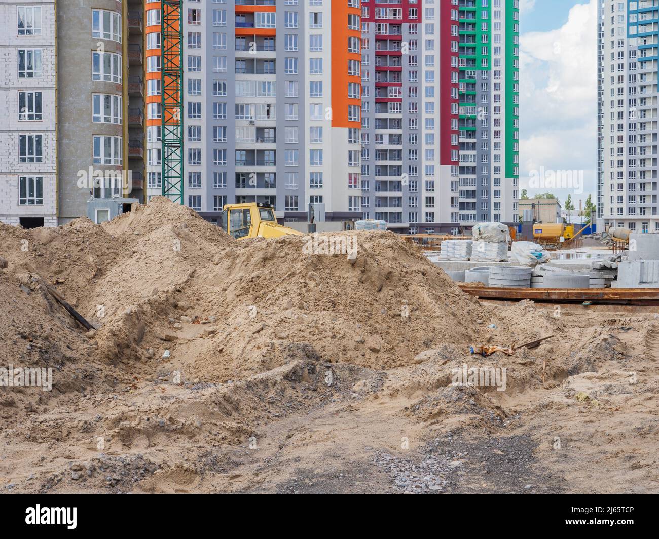 A building site with heaps of sand, concrete rings in the foreground ...