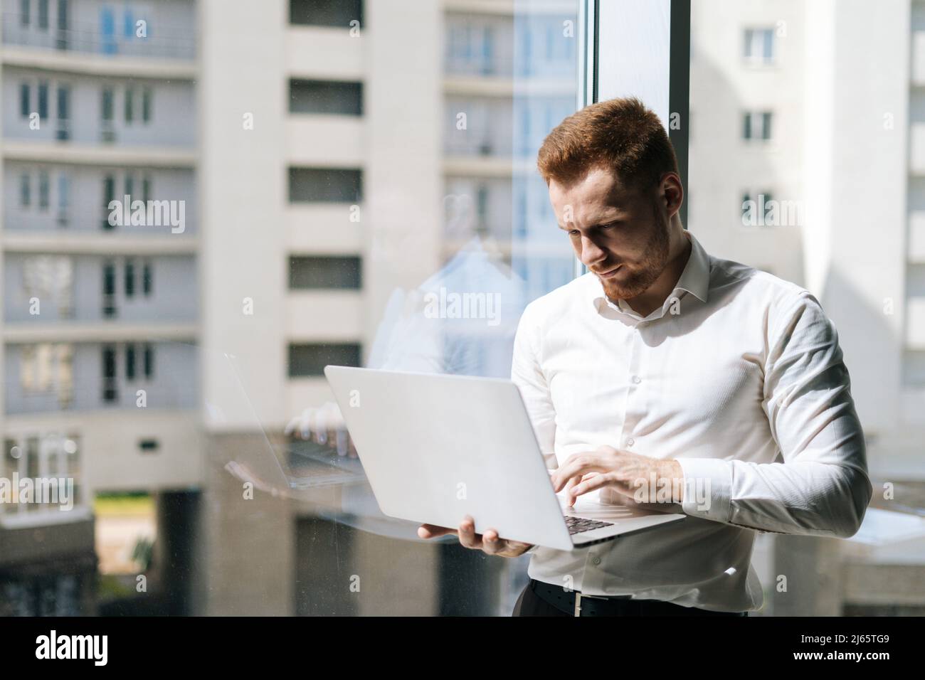 Medium shot portrait of focused young man working typing on laptop ...