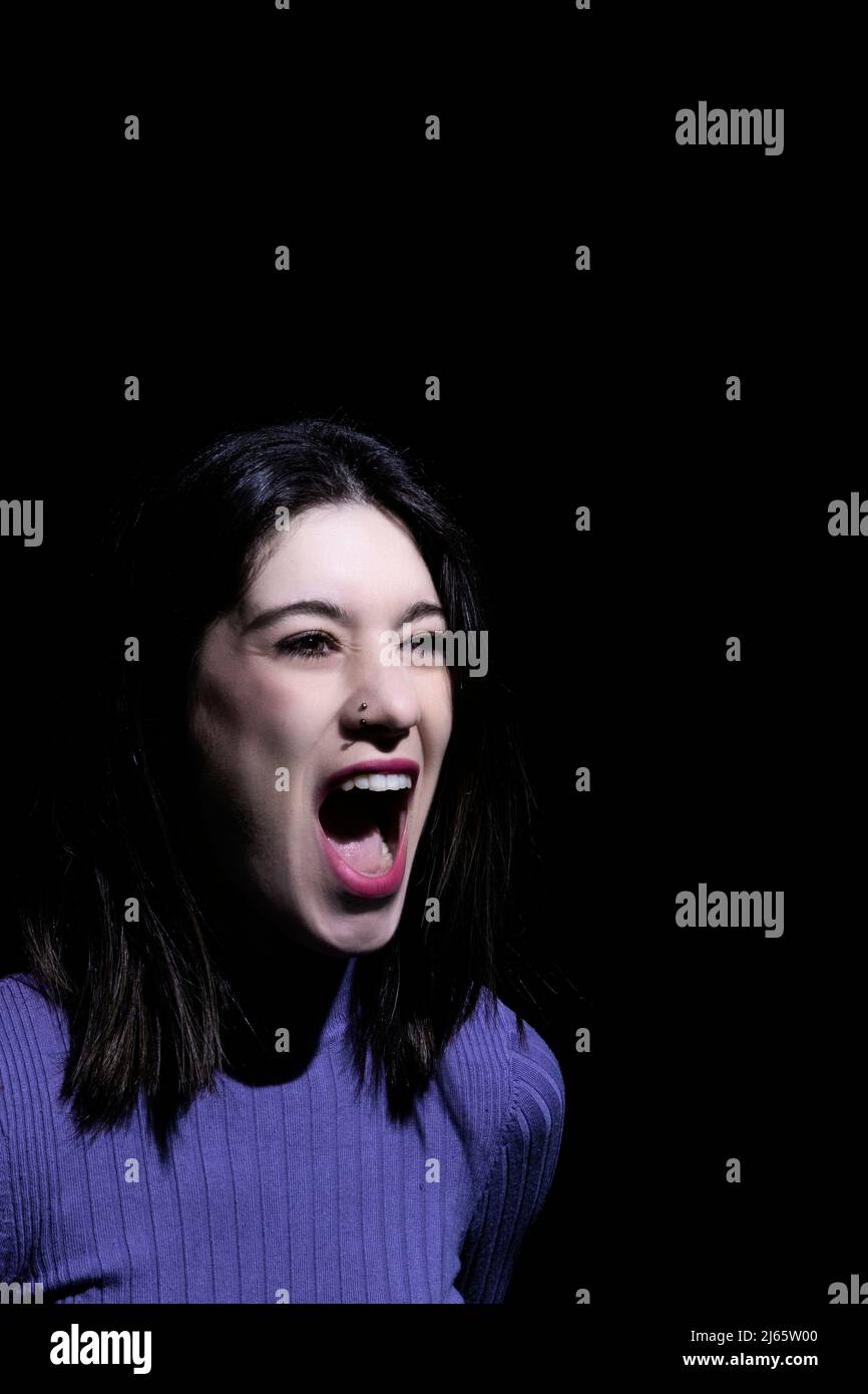 angry brunette woman screaming on a black background Stock Photo - Alamy