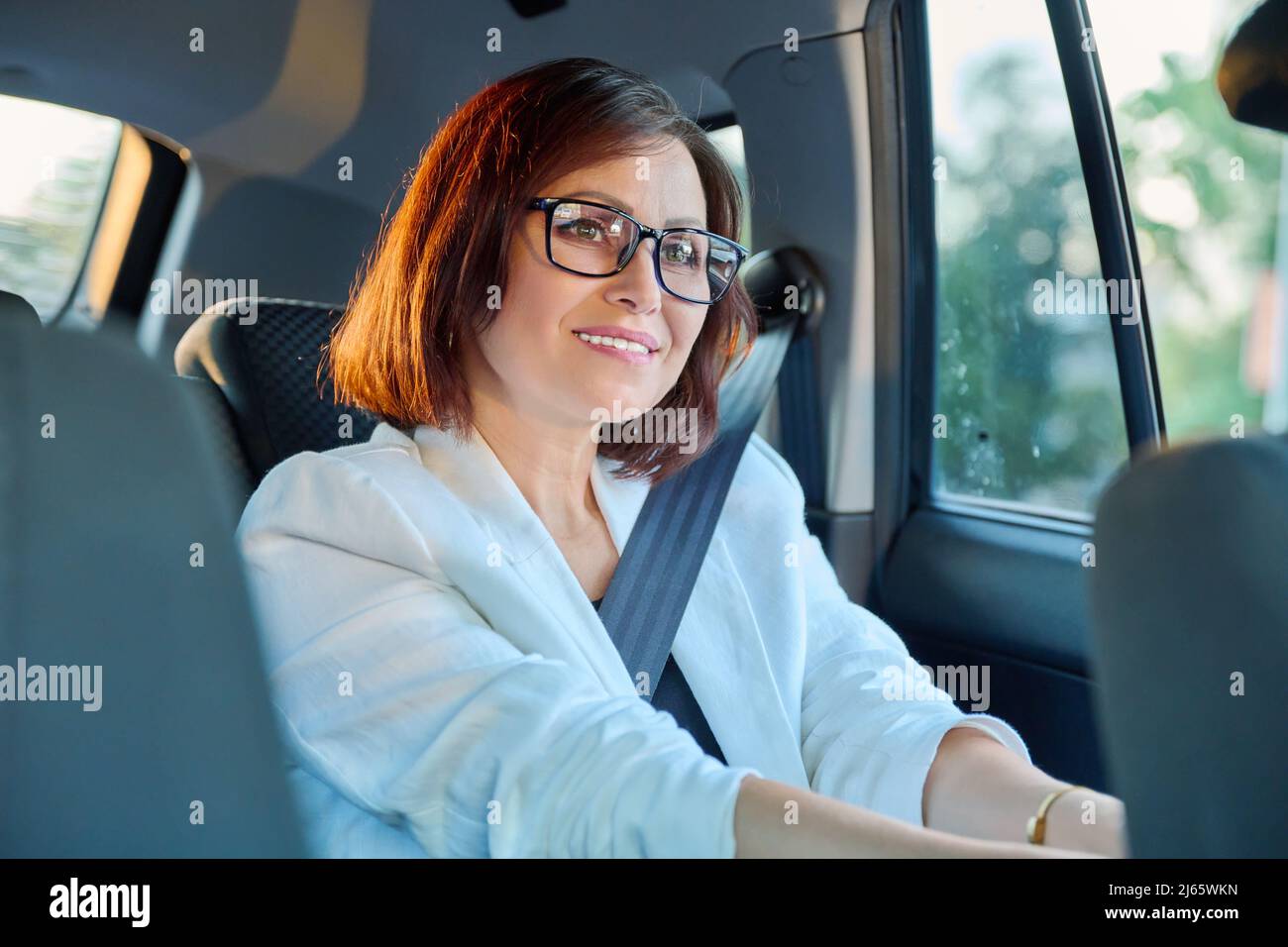 Portrait of business elegant middle-aged woman in car in back passenger ...