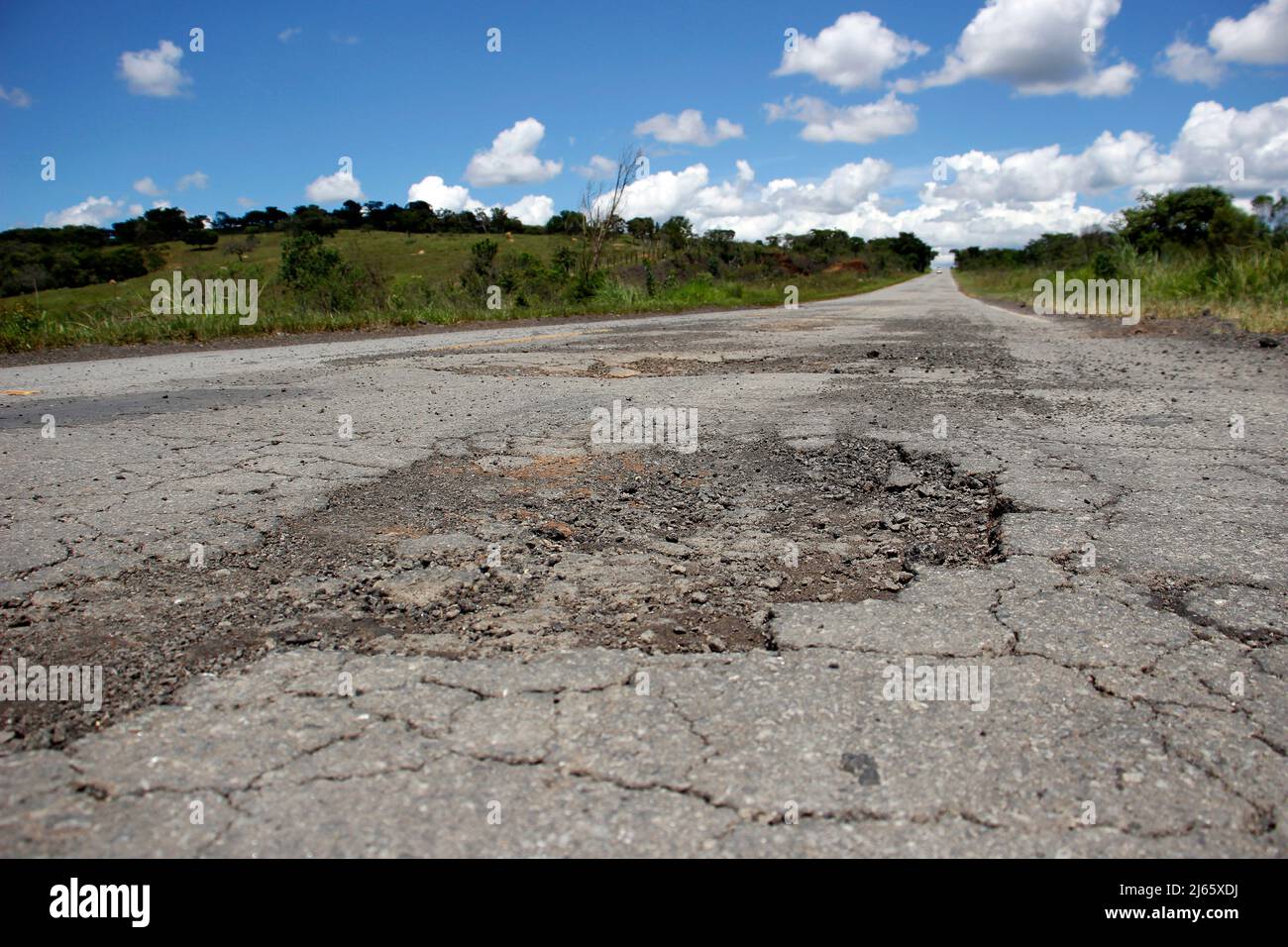 stretch of road with defective and spoiled asphalt, potholes and danger ...