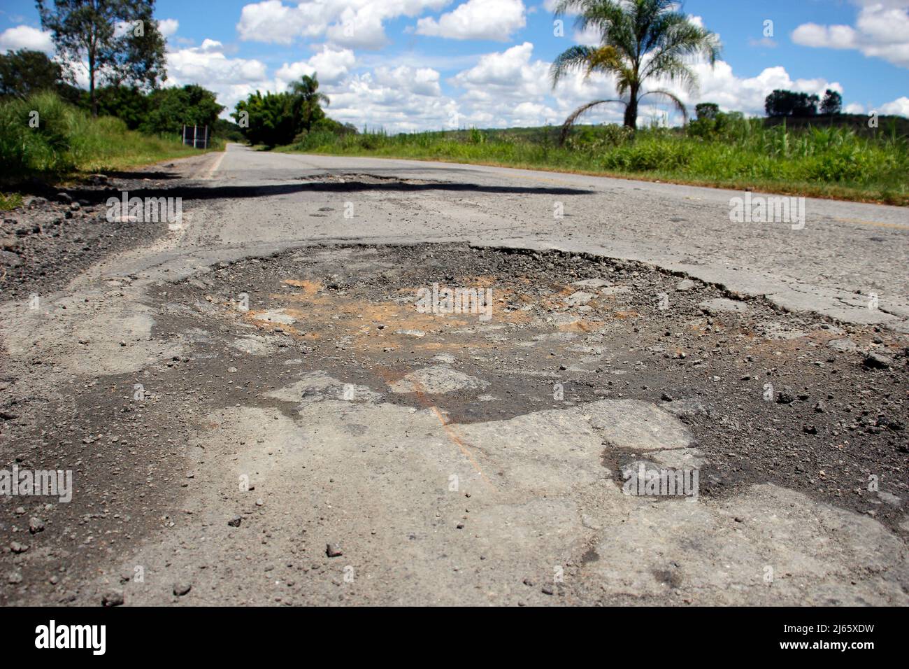 stretch of road with defective and spoiled asphalt, potholes and danger ...