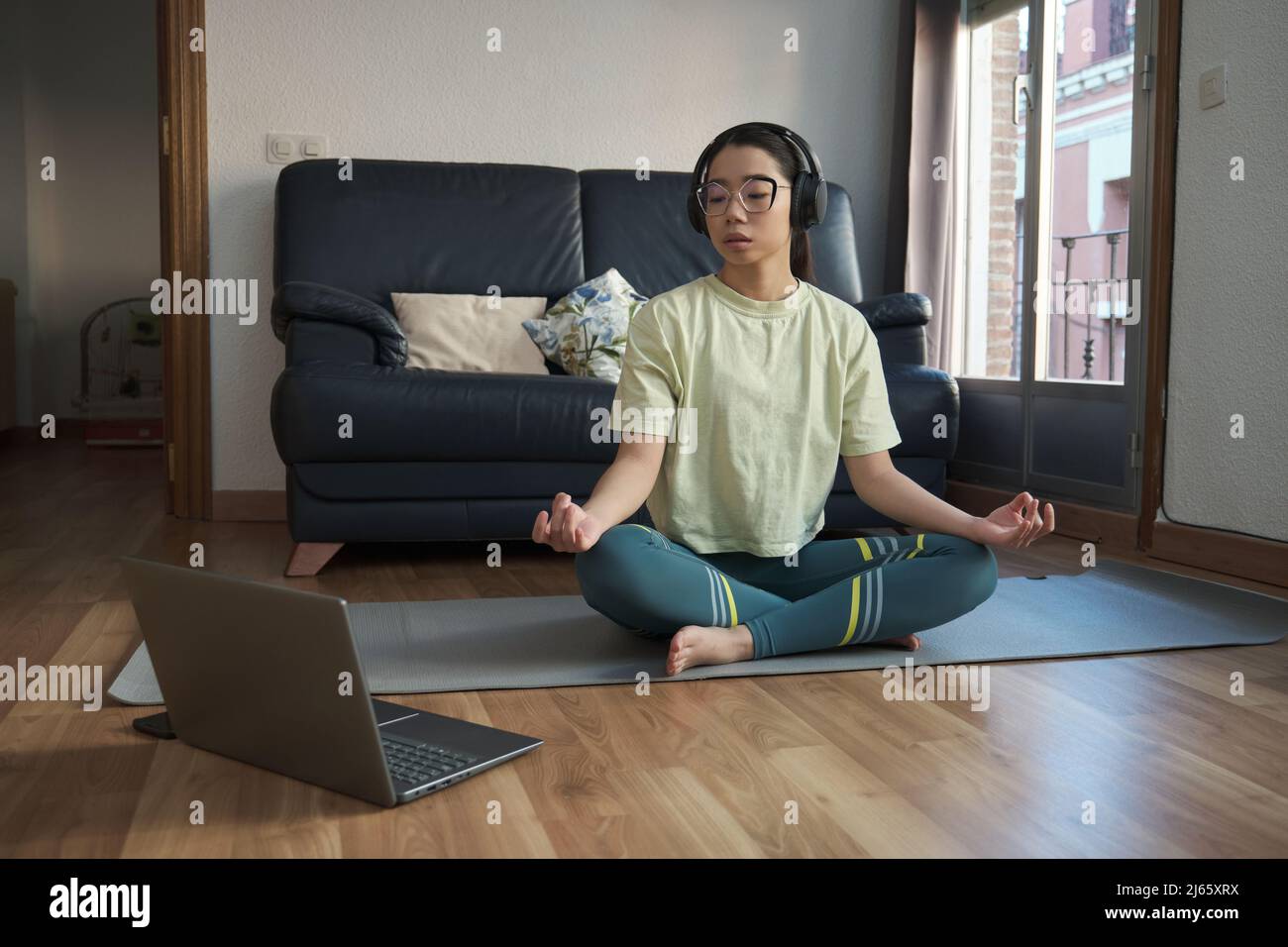 Young asian woman meditating following a meditation online class on her ...
