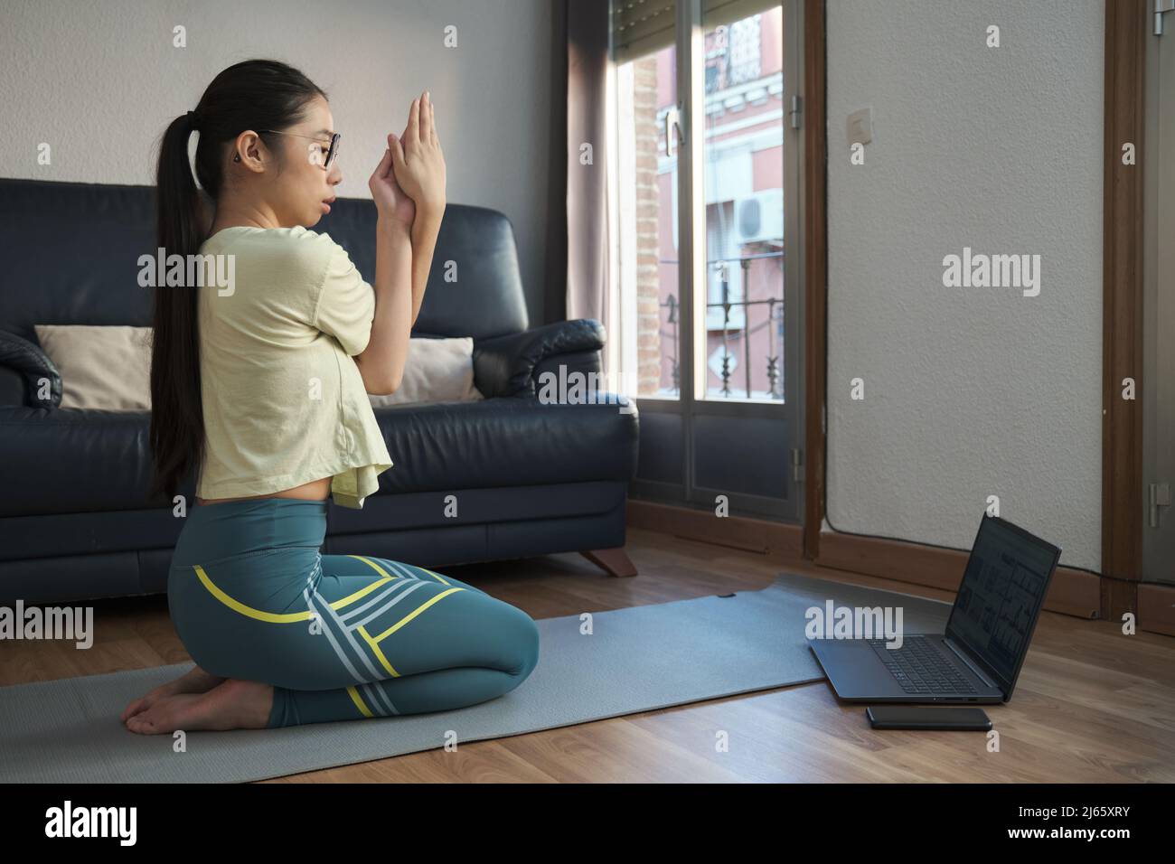 Young asian woman doing the hero pose with eagle arms at home Stock ...