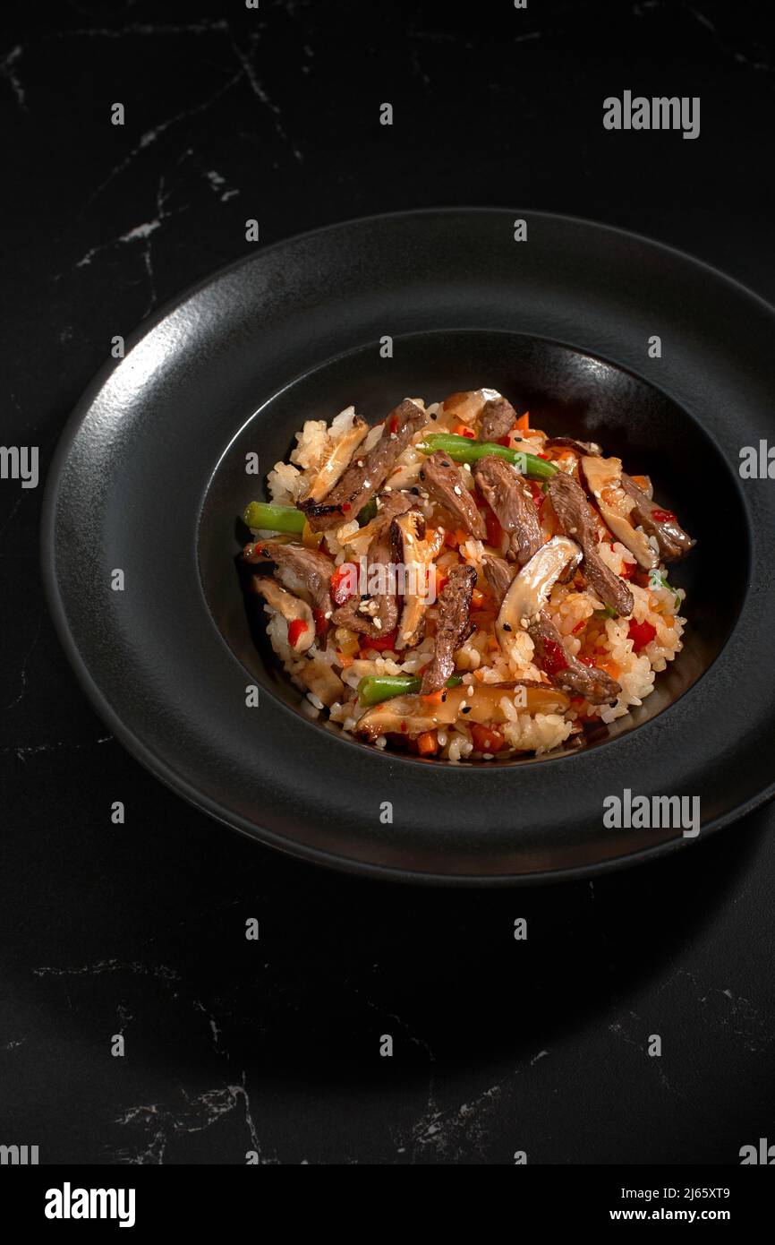 Chinese rice with beef and vegetables on a dark stone background. Asian ...