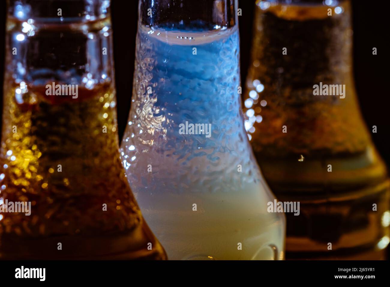 glass bottle with alcoholic liquor inside on different colours close up ...
