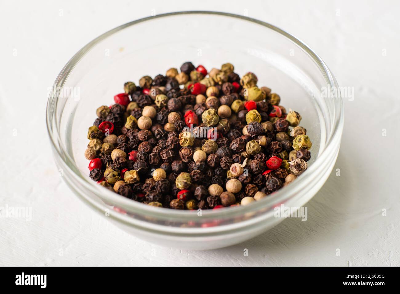 Different types of peppers in a glass plate. White background. Macro ...